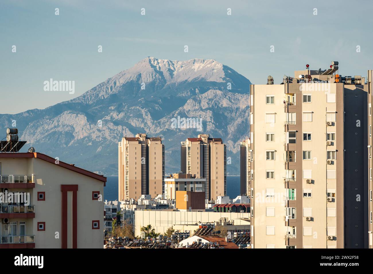Snowy mountain peak visible through city buildings on a sunny day Stock ...