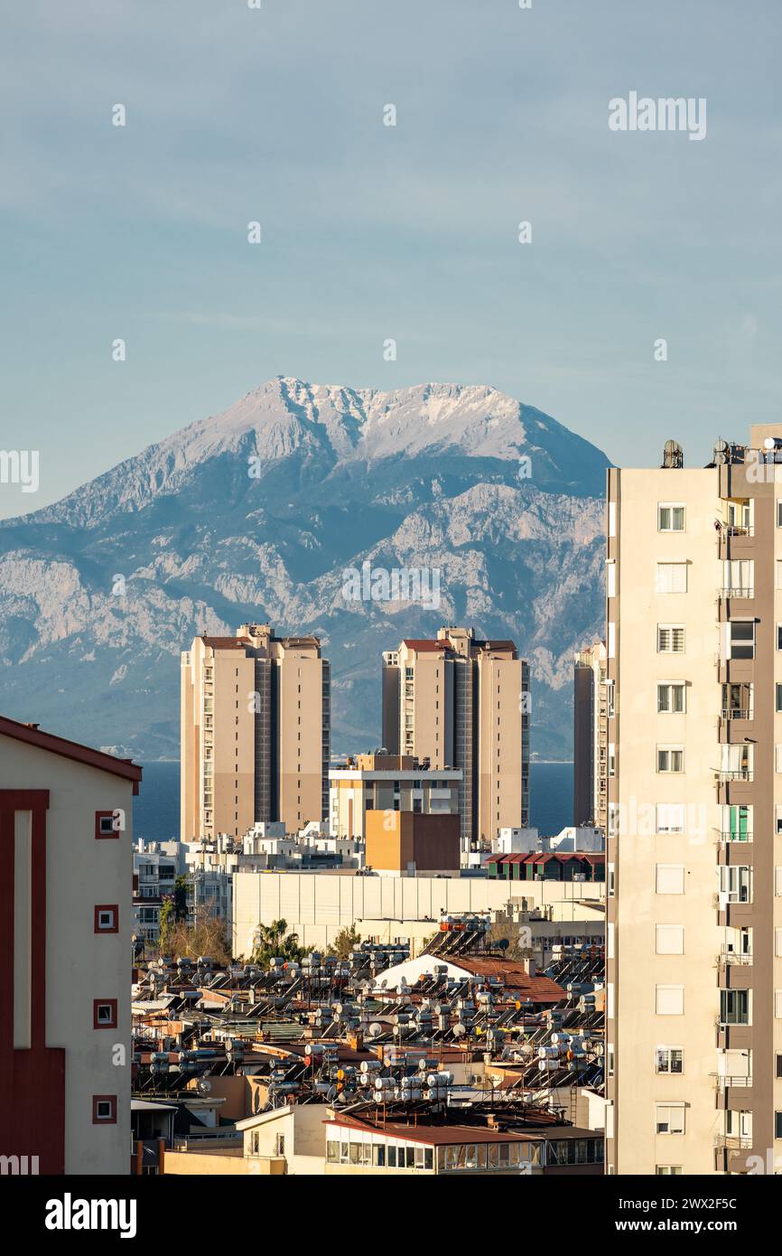 Snowy mountain peak visible through city buildings on a sunny day Stock ...
