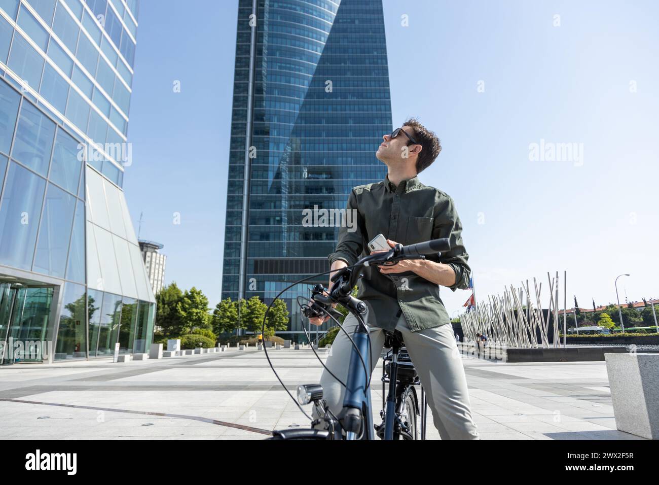 young businessman rides e-bike on his way to the tower where his office ...