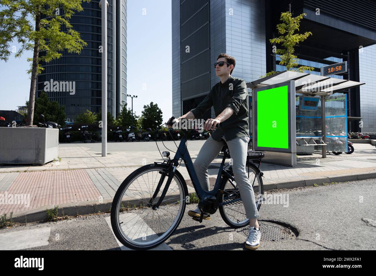 young businessman rides e-bike on his way to the tower where his office ...