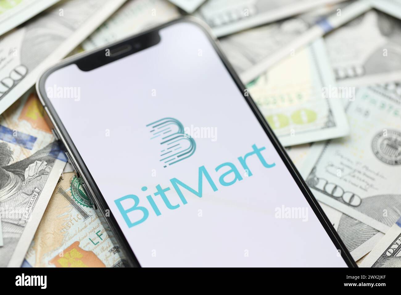 KYIV, UKRAINE - MARCH 15, 2024 Bitmart logo on iPhone display screen with many hundred dollar ...