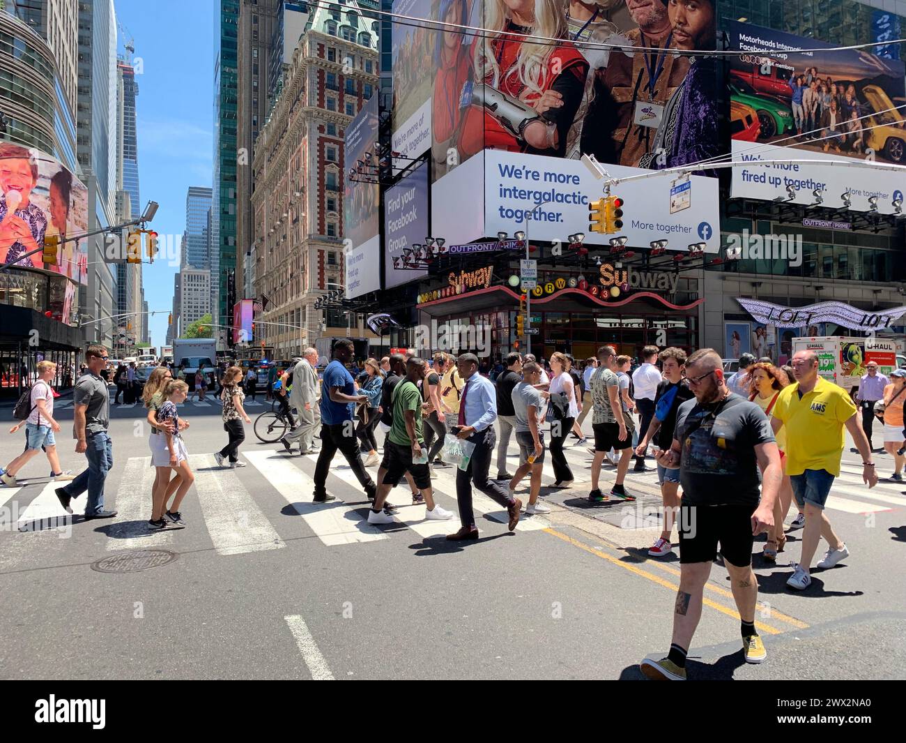 A crowd of people cross the street in the heart of New York City Times ...