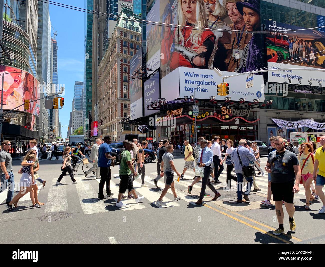 A crowd of people cross the street in the heart of New York City Times ...