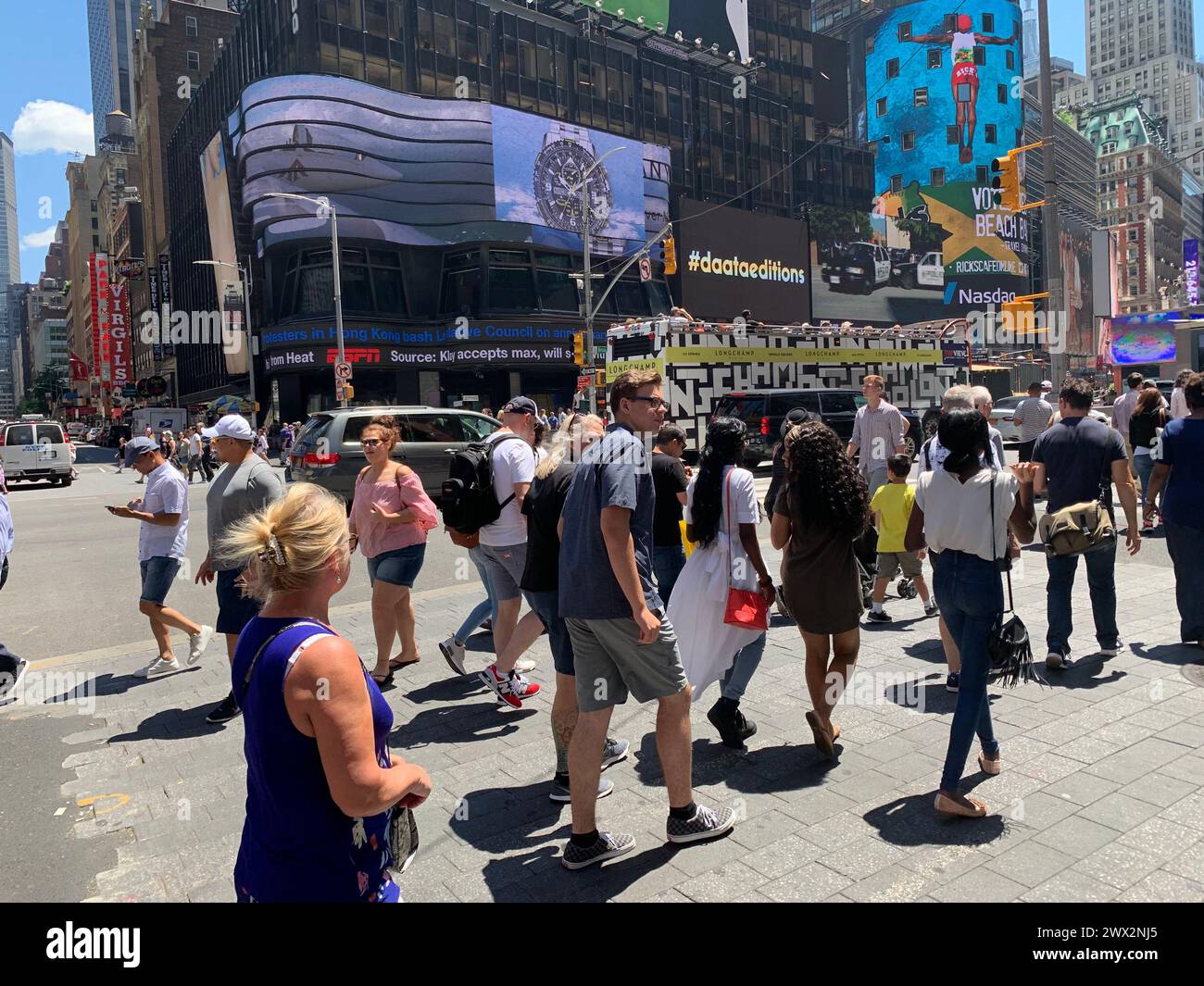 A large group of pedestrians cross the street at the crosswalk in the ...