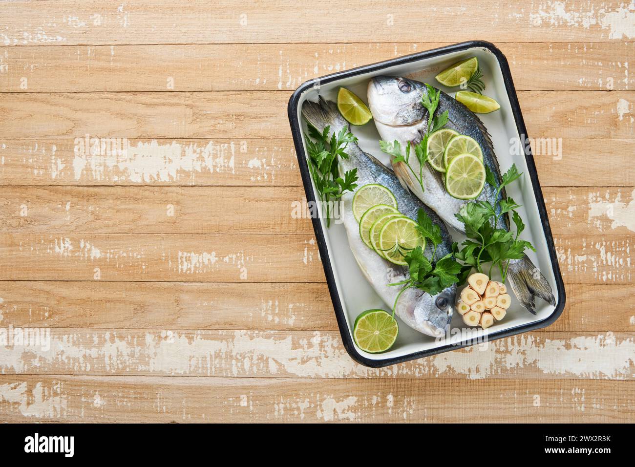 Raw fresh. Fresh raw dorado with lemon, lime, parsley and salt on old ...