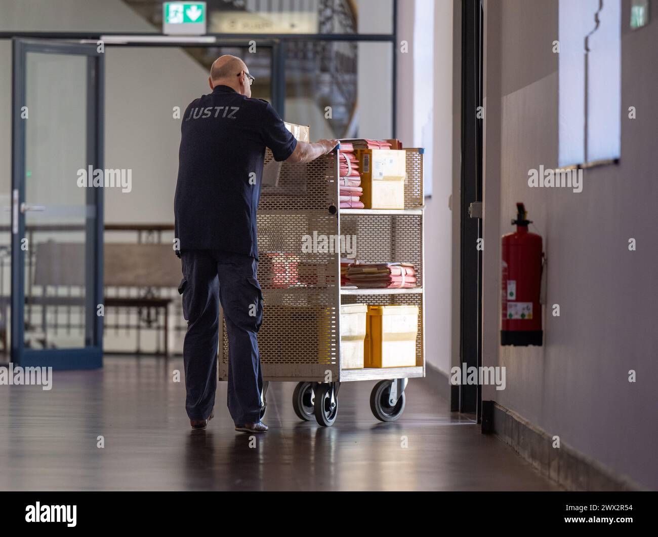 PRODUCTION - 27 March 2024, Berlin: A prison officer pushes a full file ...