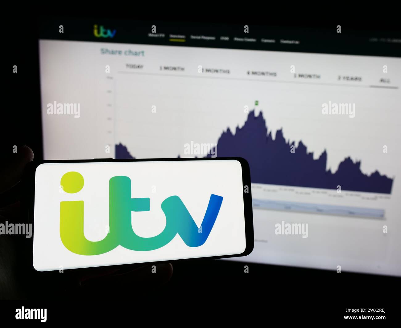 Person holding mobile phone with logo of British media and broadcasting company ITV plc in front ...