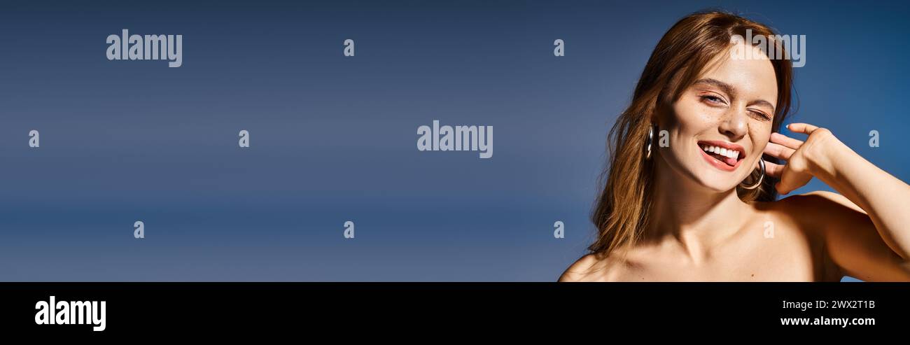 Smiling woman making funny winky face with tongue, touching her ear on ...