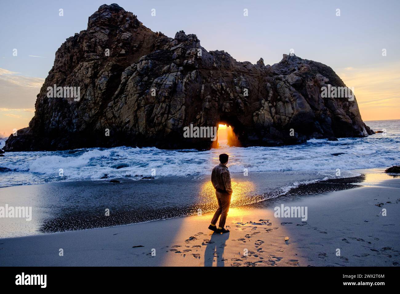Sunset illuminates person in front of Window in the Rock feature of ...