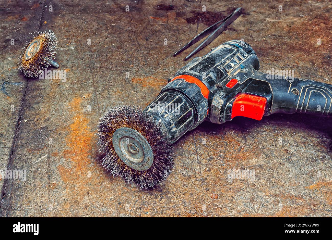 Close-up of worn electric drill with cleaning attachment and tweezers ...
