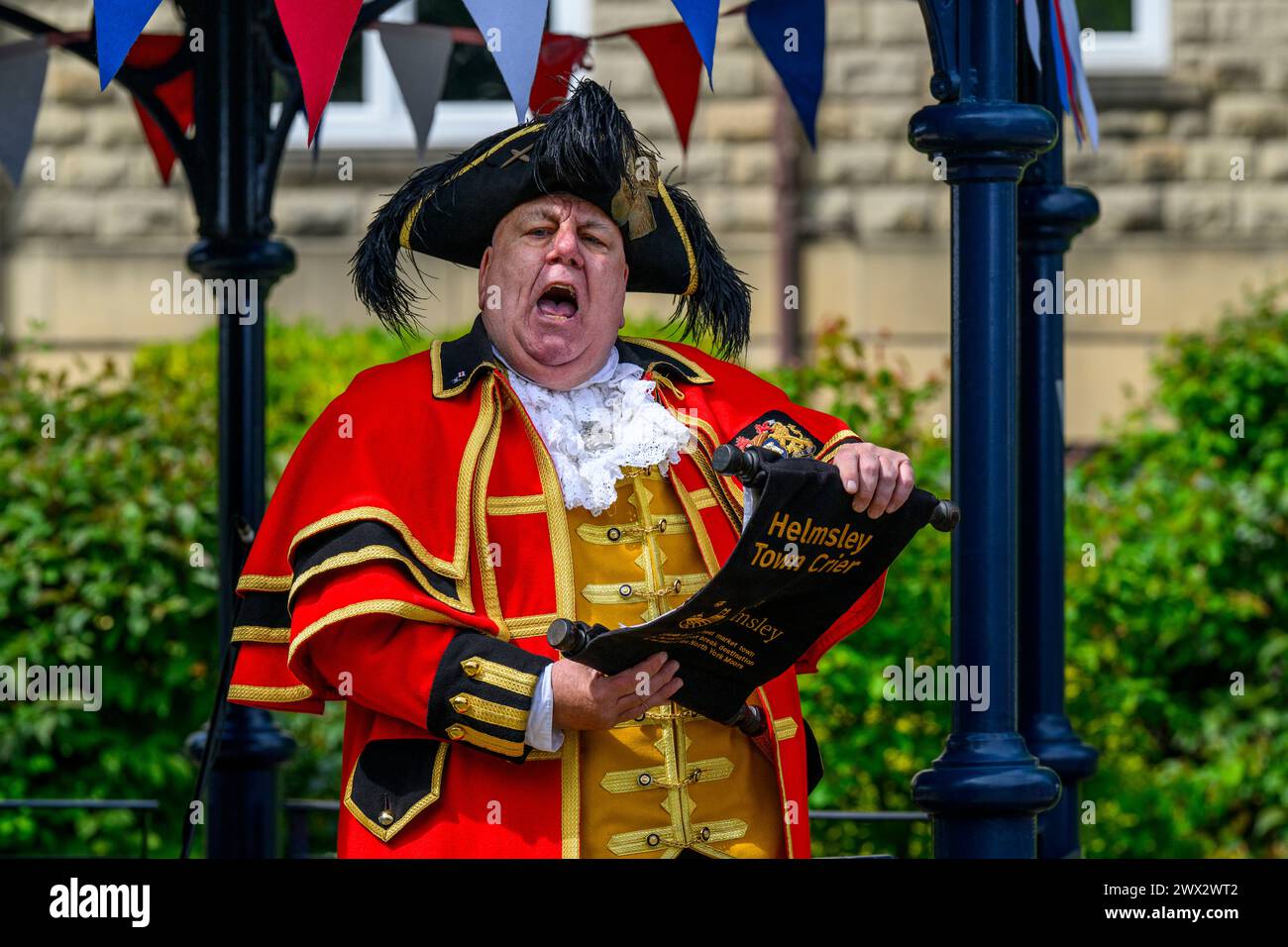 Male town crier (colourful braided crier's uniform) proclaiming, making ...