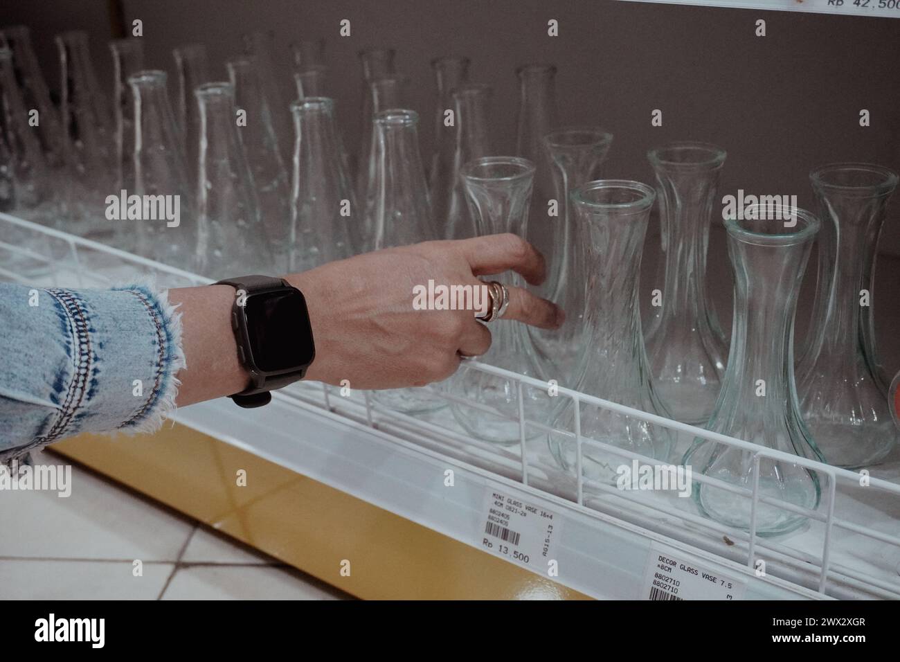 The hand is wearing a watch and is picking up a clear flower pot from ...