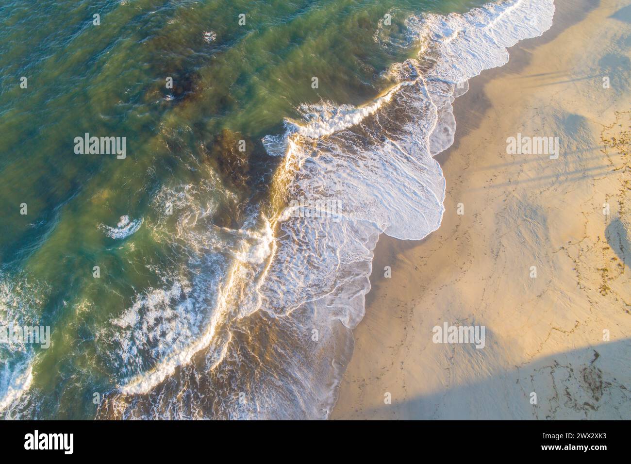 drone aerial overhead view of waves breaking on the shore of a beach at ...