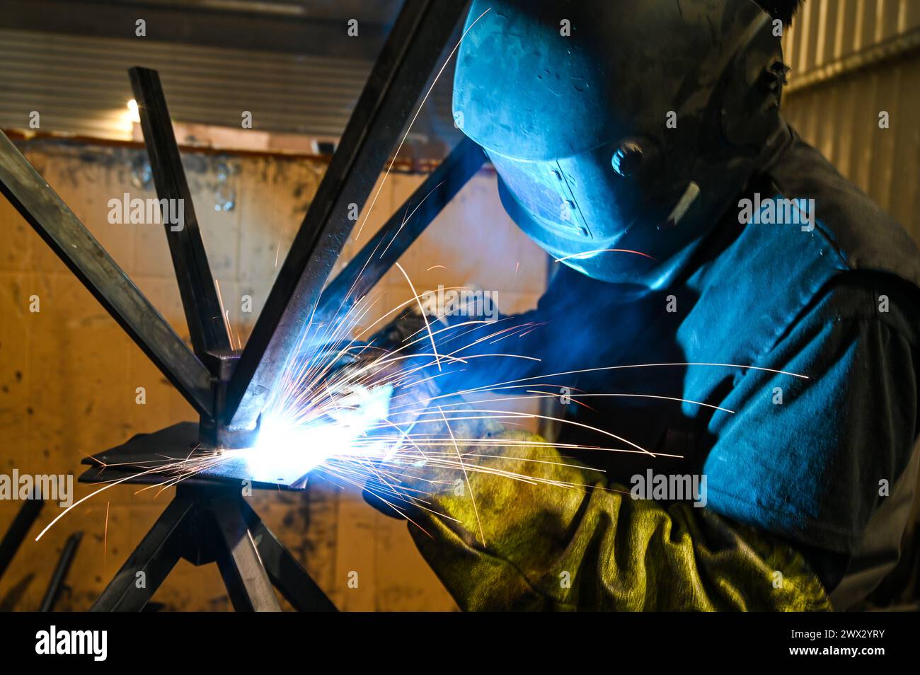 Welder at work. Welding sparkles. Male worker wearing helmet and gloves ...