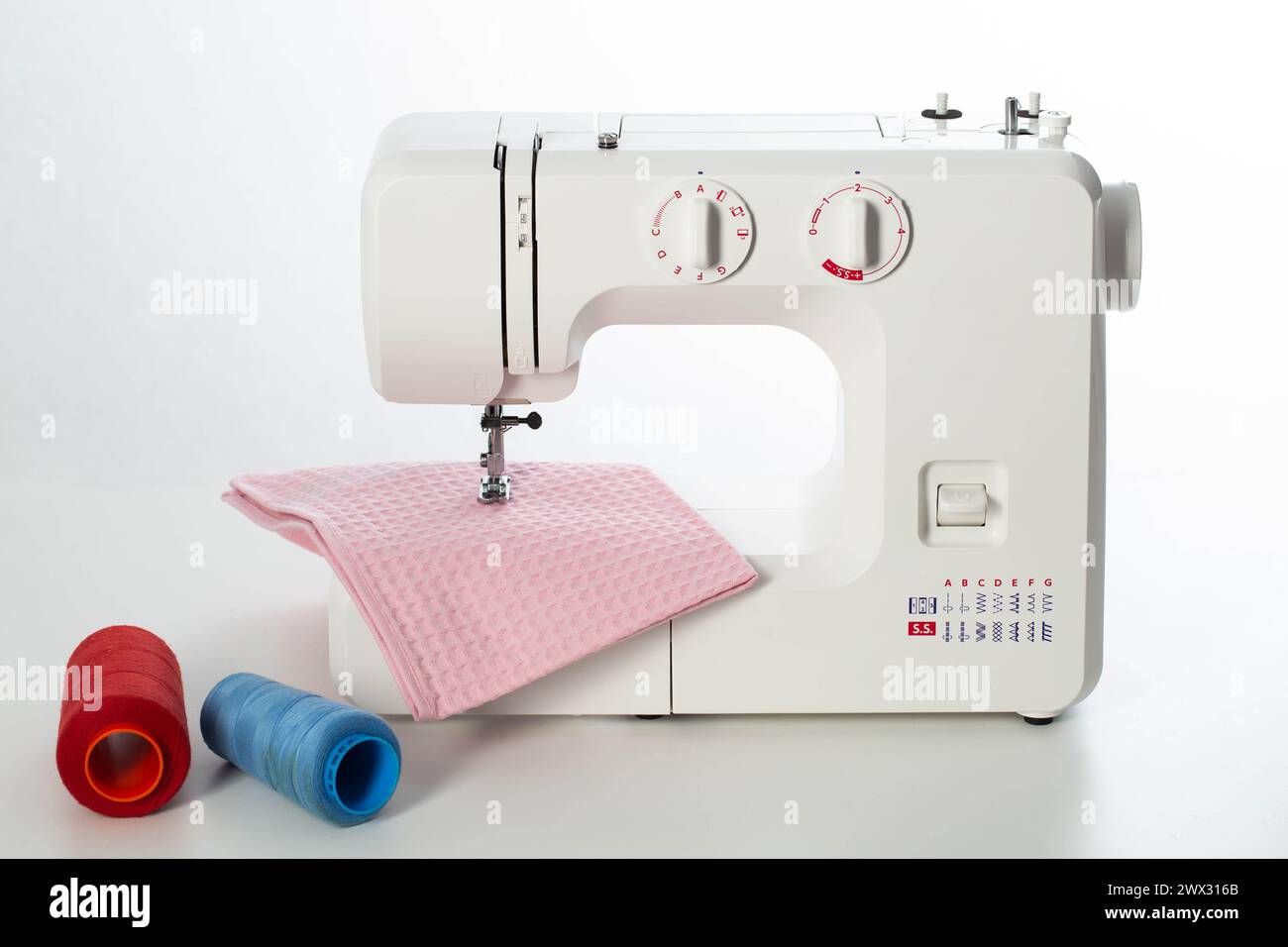 Modern automatic white sewing machine with pink fabric and multi ...