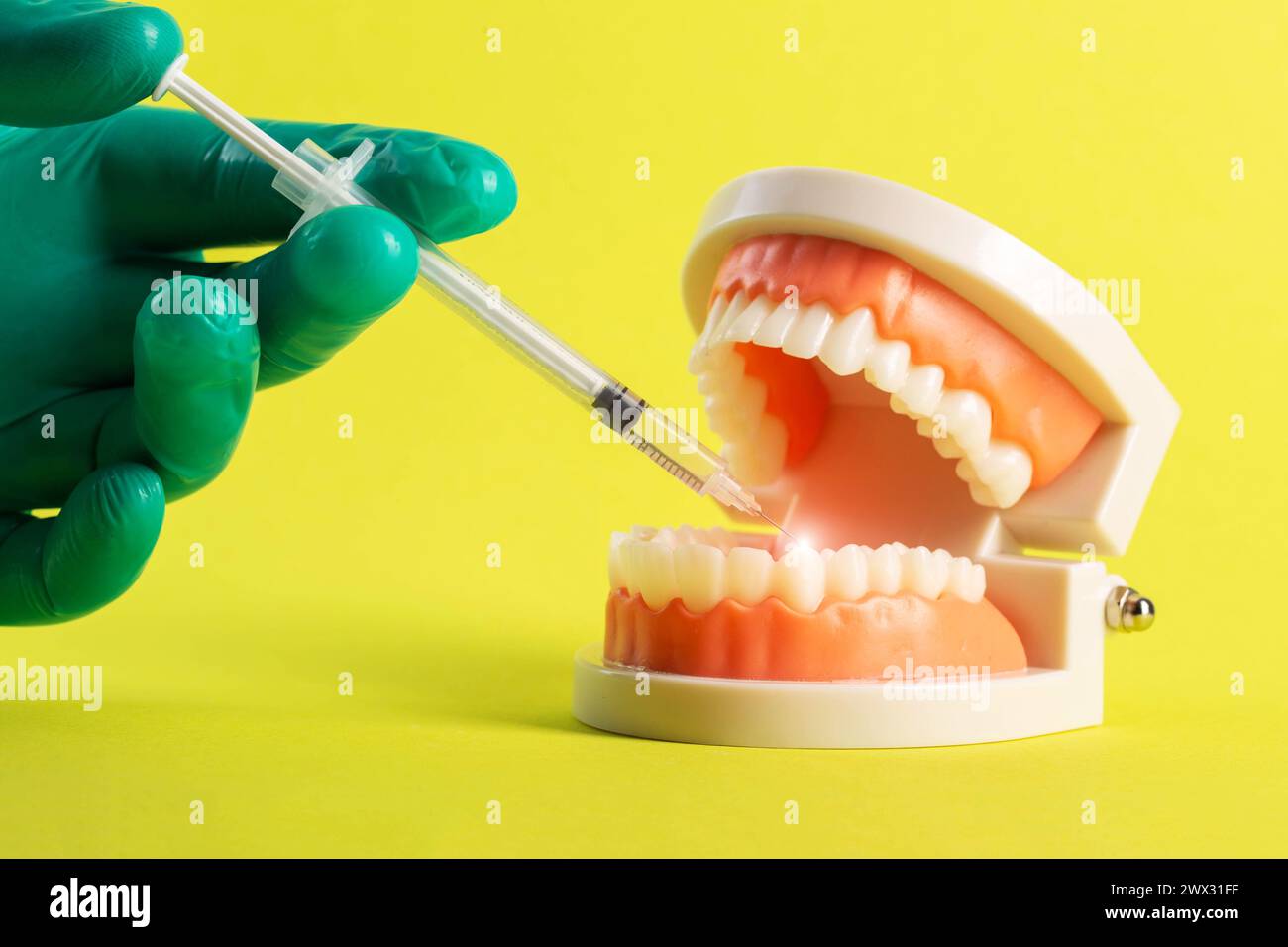 The hand of a dentist doctor in a green medical glove makes an ...