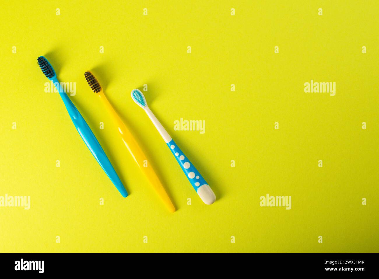 Three toothbrushes yellow and blue on a yellow background. Family ...