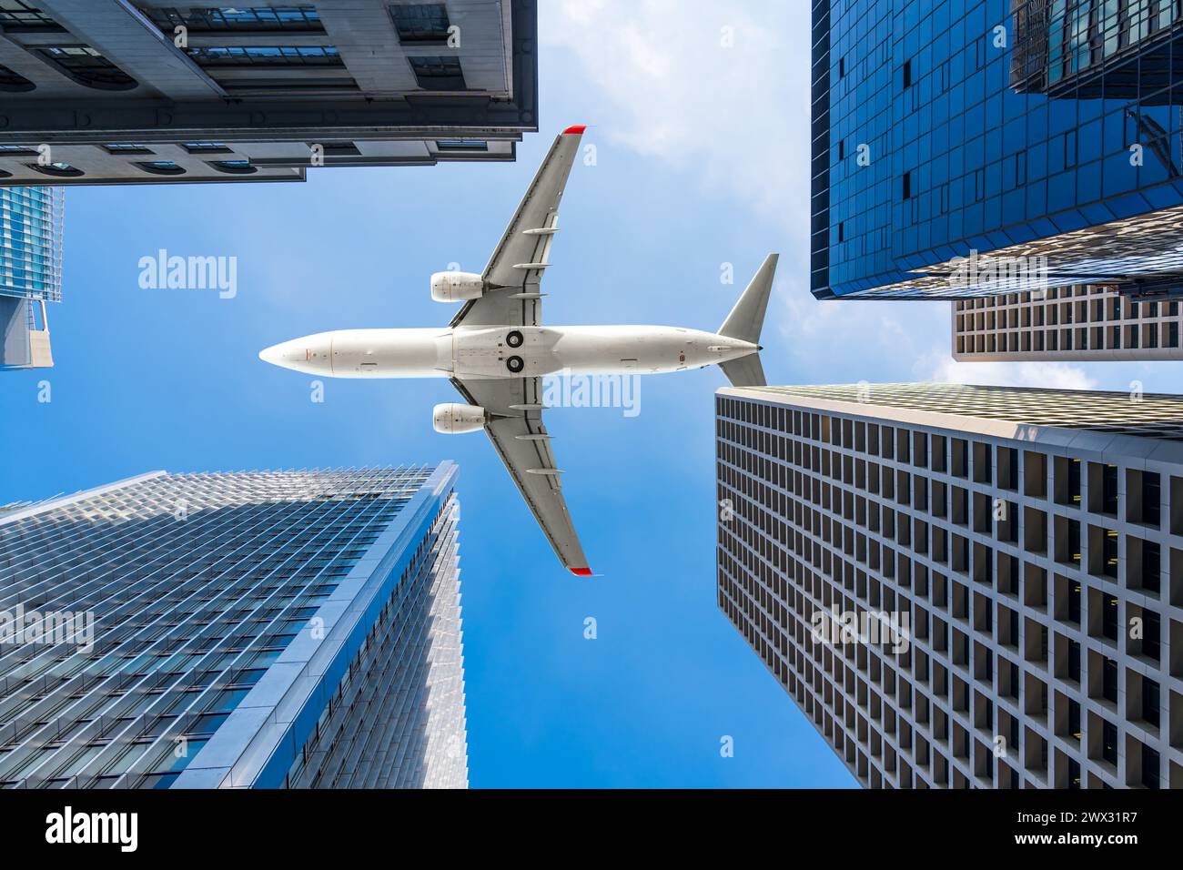 Airplane jet flying above in the sky among tall buildings in a modern ...