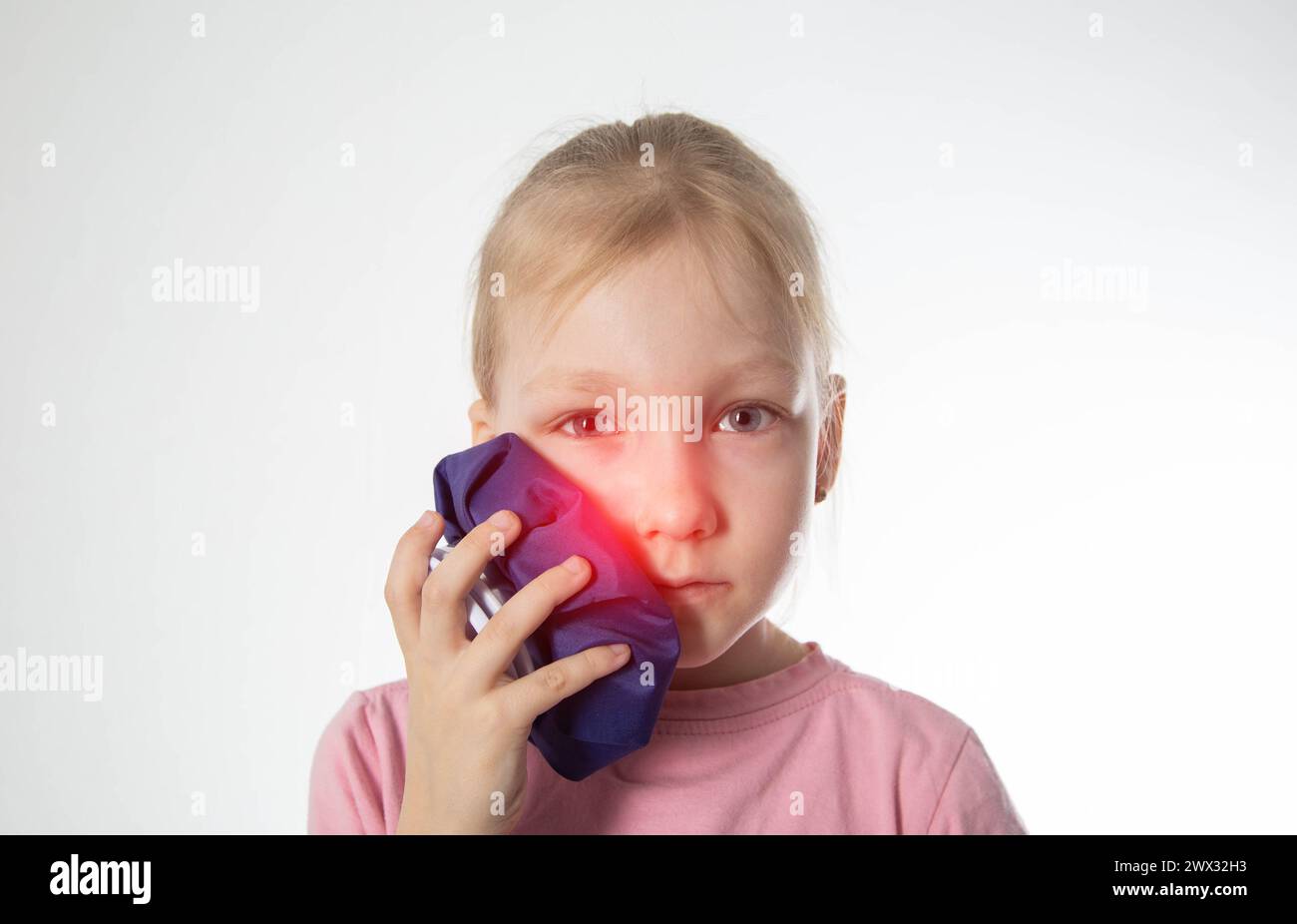 A seven-year-old girl applies a cold compress to a sore tooth ...