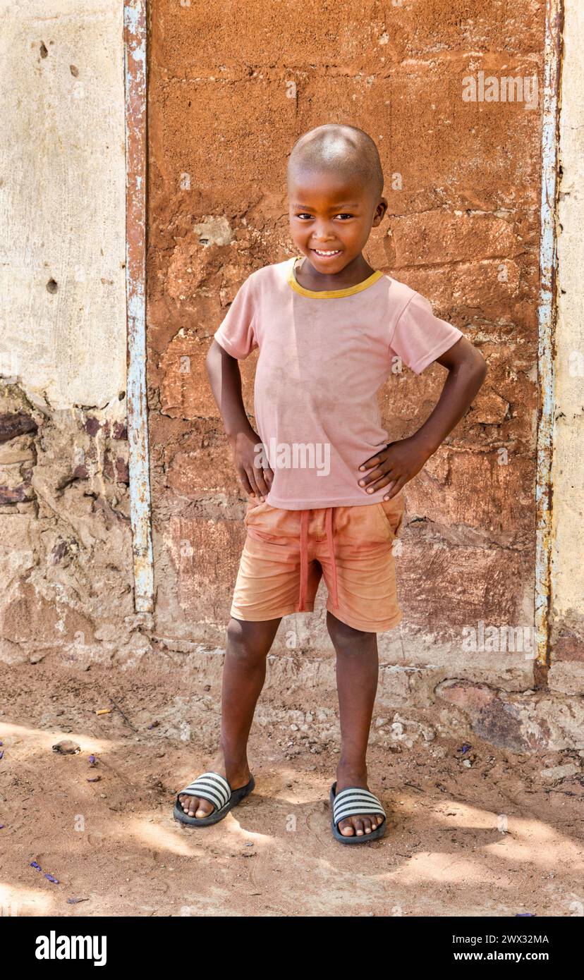 single african child in a village, posing in front of the house brown ...