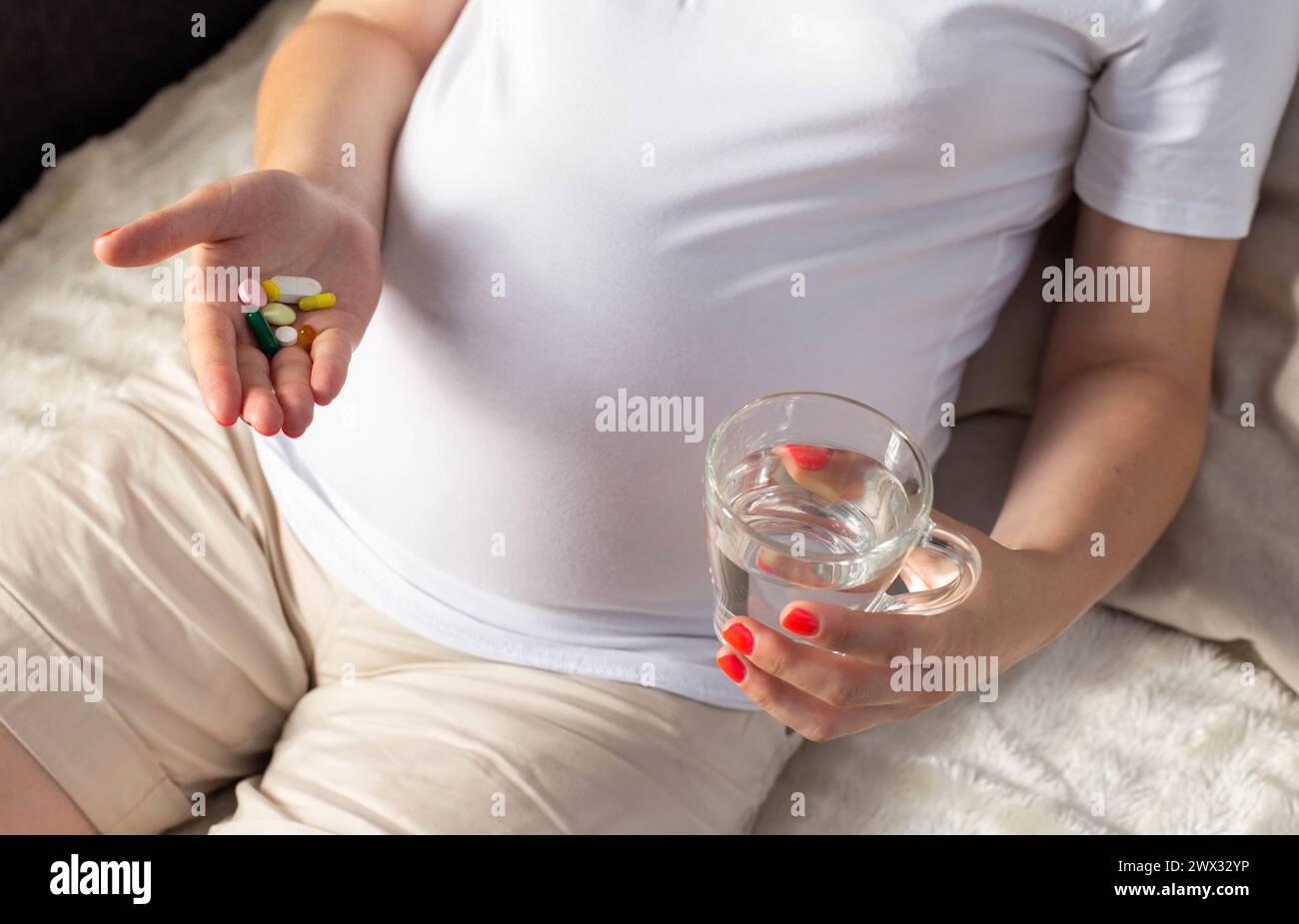 A pregnant girl holds a handful of pills on the palm of her hand. First ...