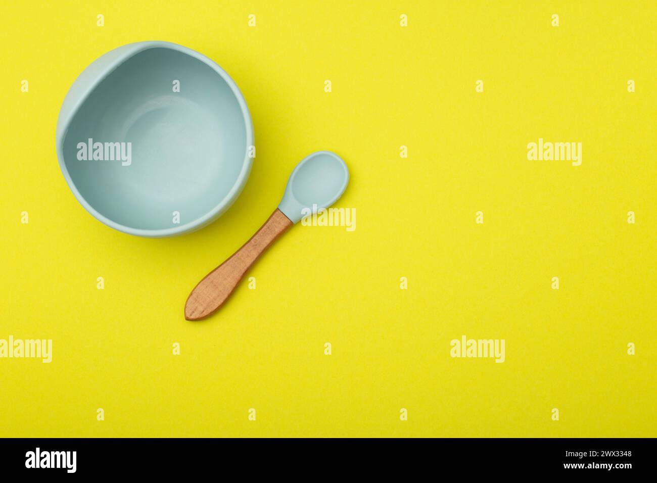 Blue children's plate and spoon on a yellow background. The concept of ...