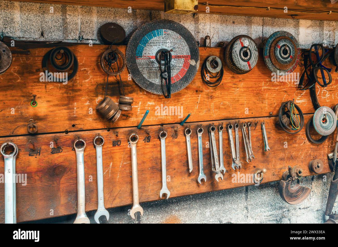 Old tools hang on wall in workshop, wrenches, grinding wheels. Vintage garage style Stock Photo ...