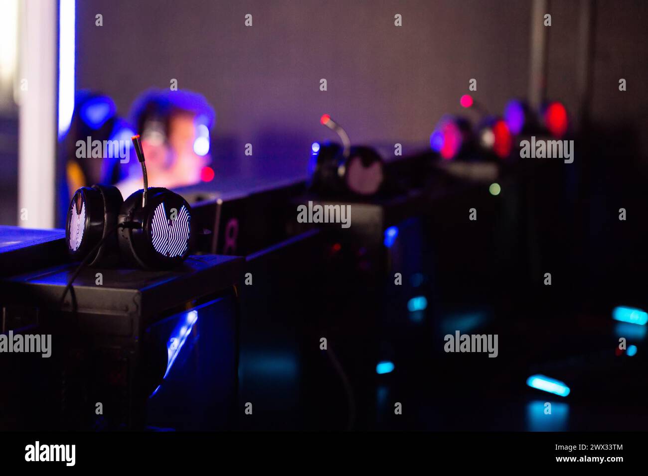 Headphones in focus in a computer club with players in the background ...
