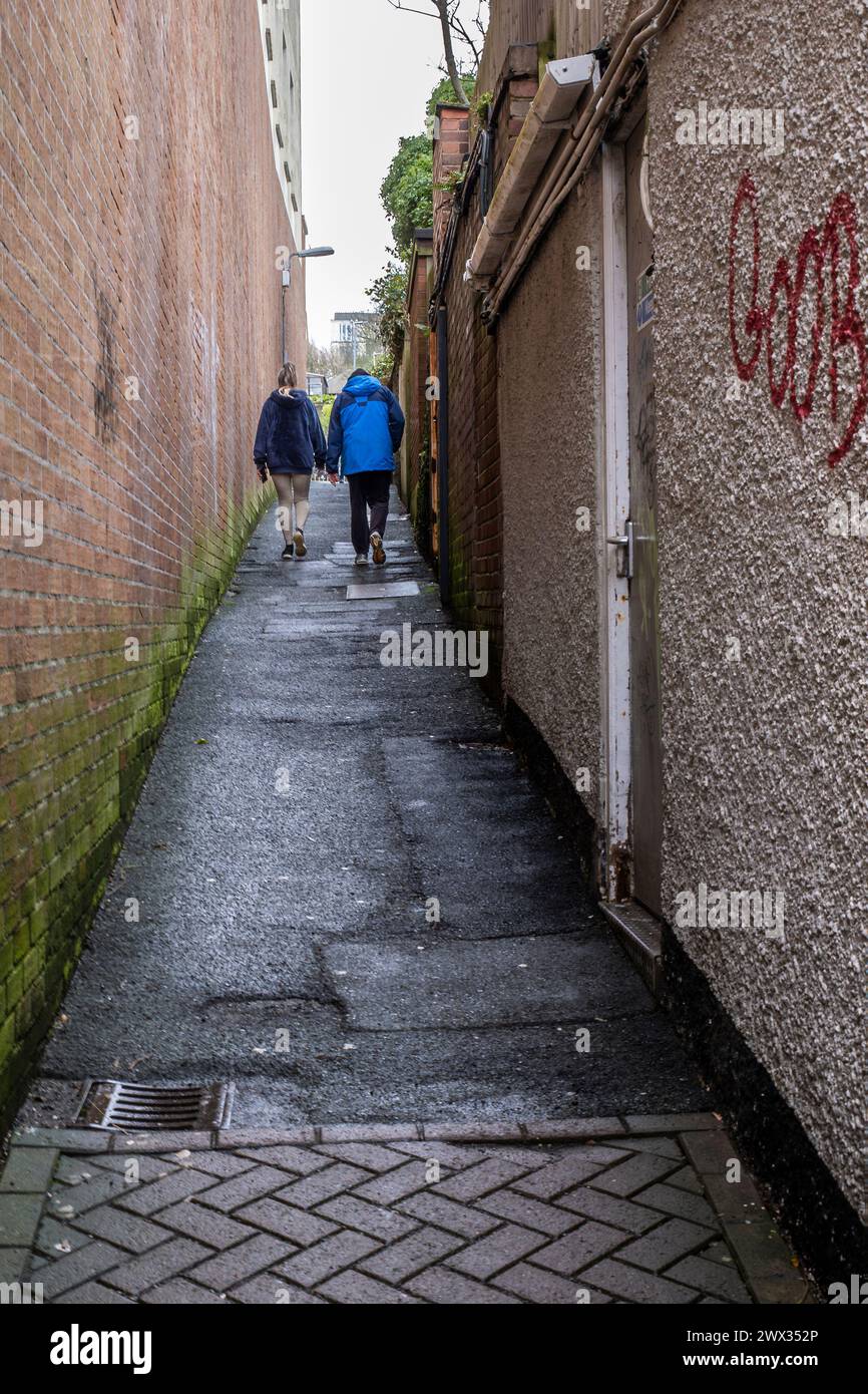 A man and a woman walking together up a sloping alleyway in Newquay ...