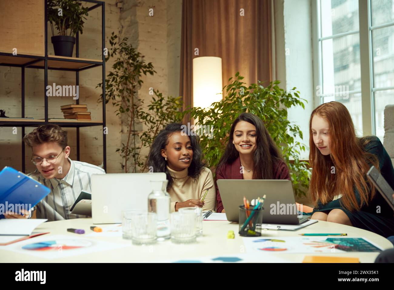 Motivated young people, students sitting at table with laptops, doing ...