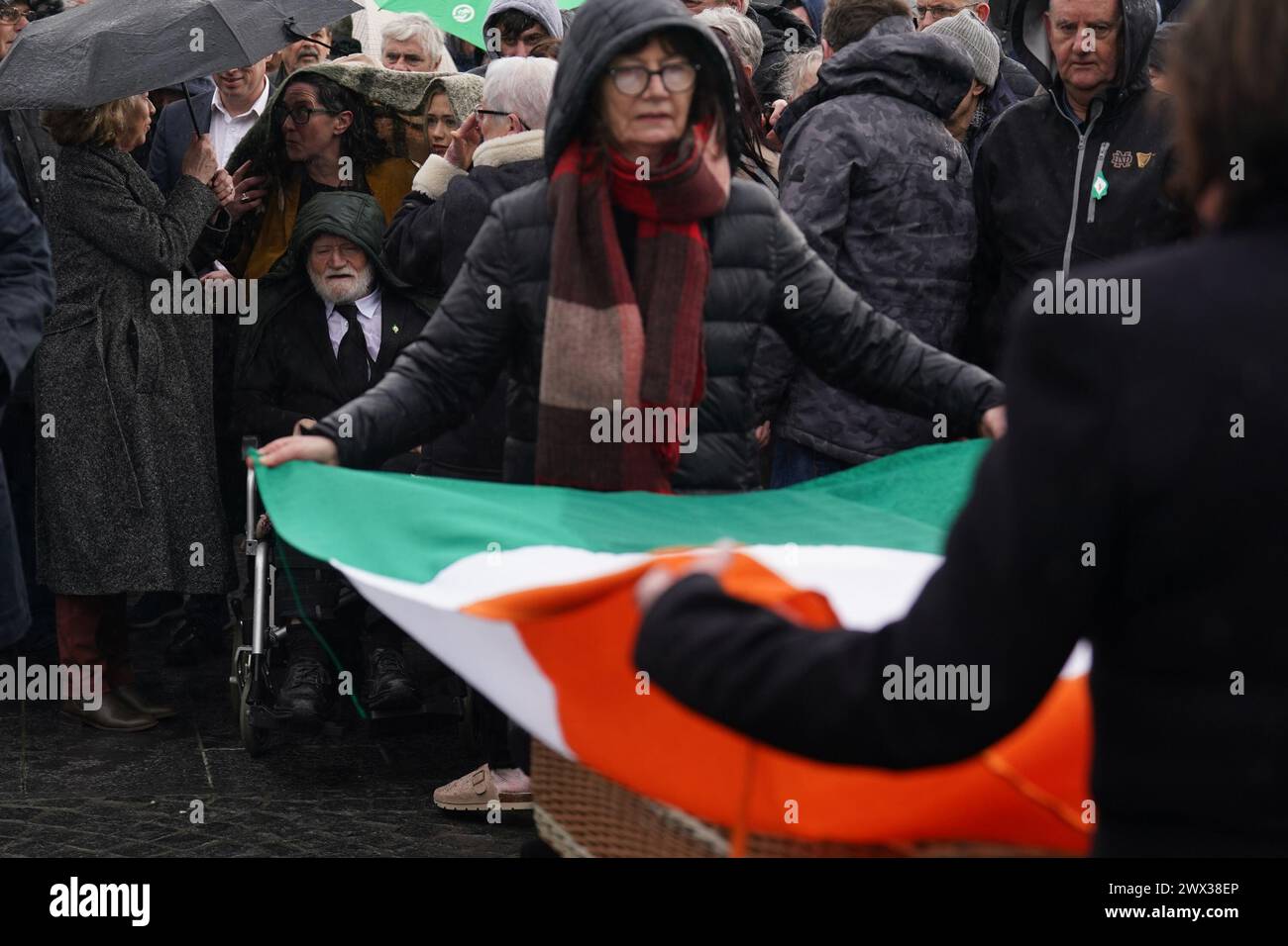 Jim Monaghan, (in wheelchair) looks on as the tricolour is removed from ...