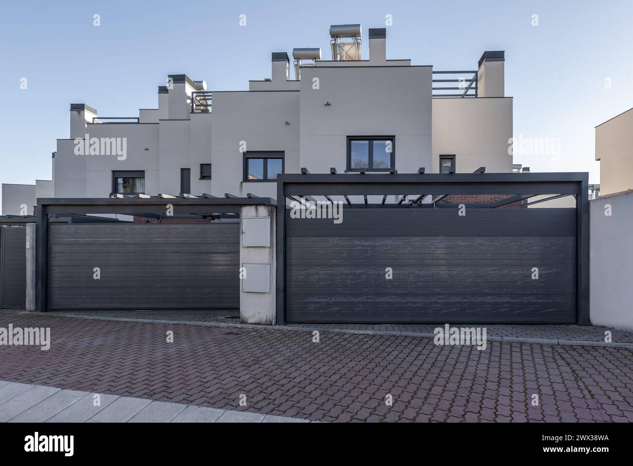 Facades of identical semi-detached houses with garage entrance with ...