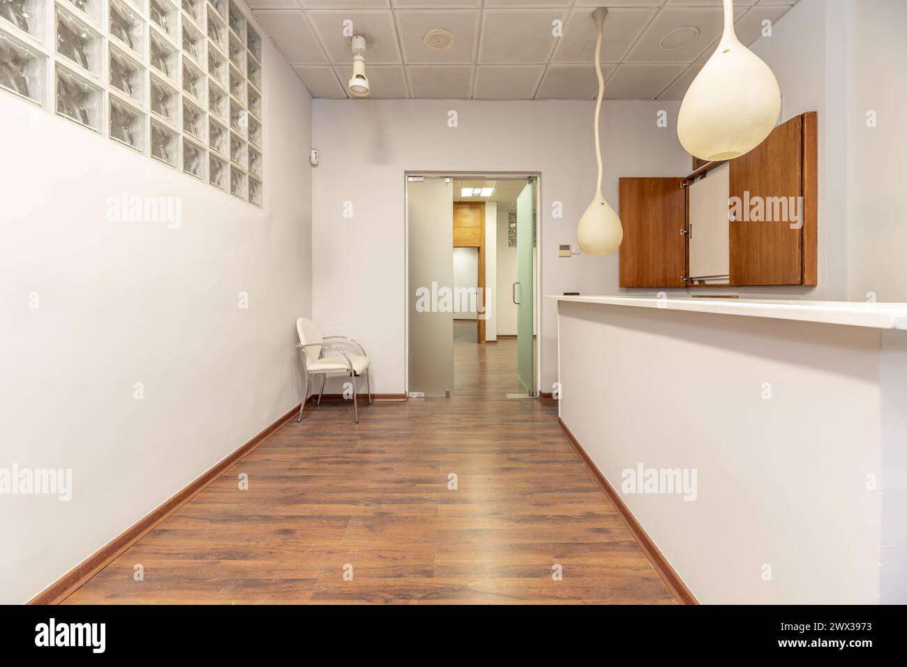 White reception desk and a wall with a glass brick skylight Stock Photo ...