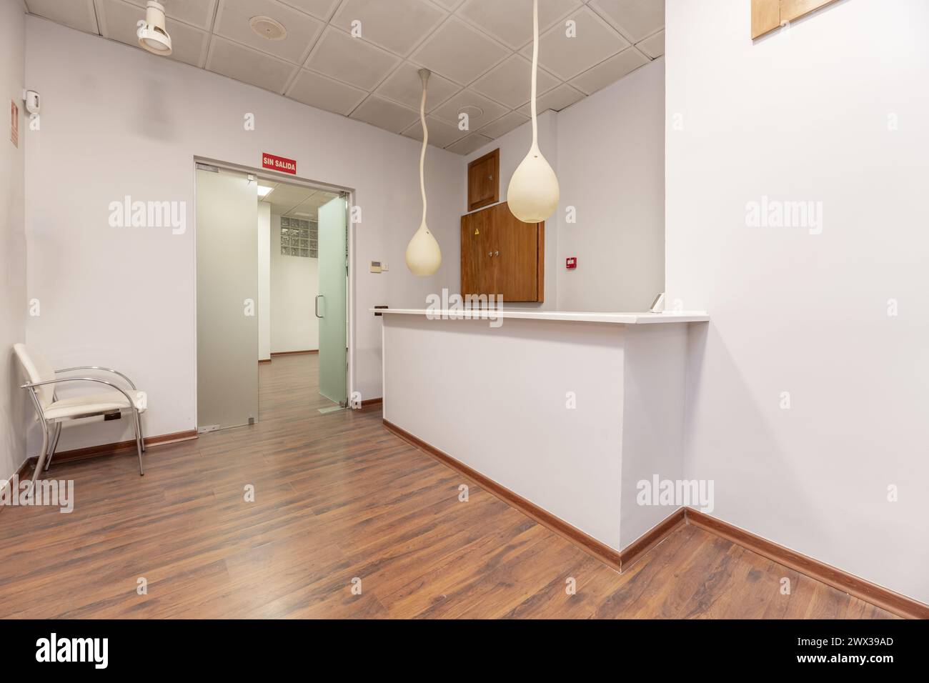 Frontal image of a white reception desk and hanging lamps above the ...