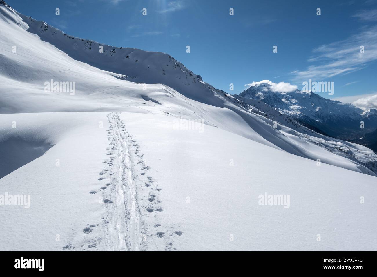 Ski touring track in pristine snow leading across the mountain side ...