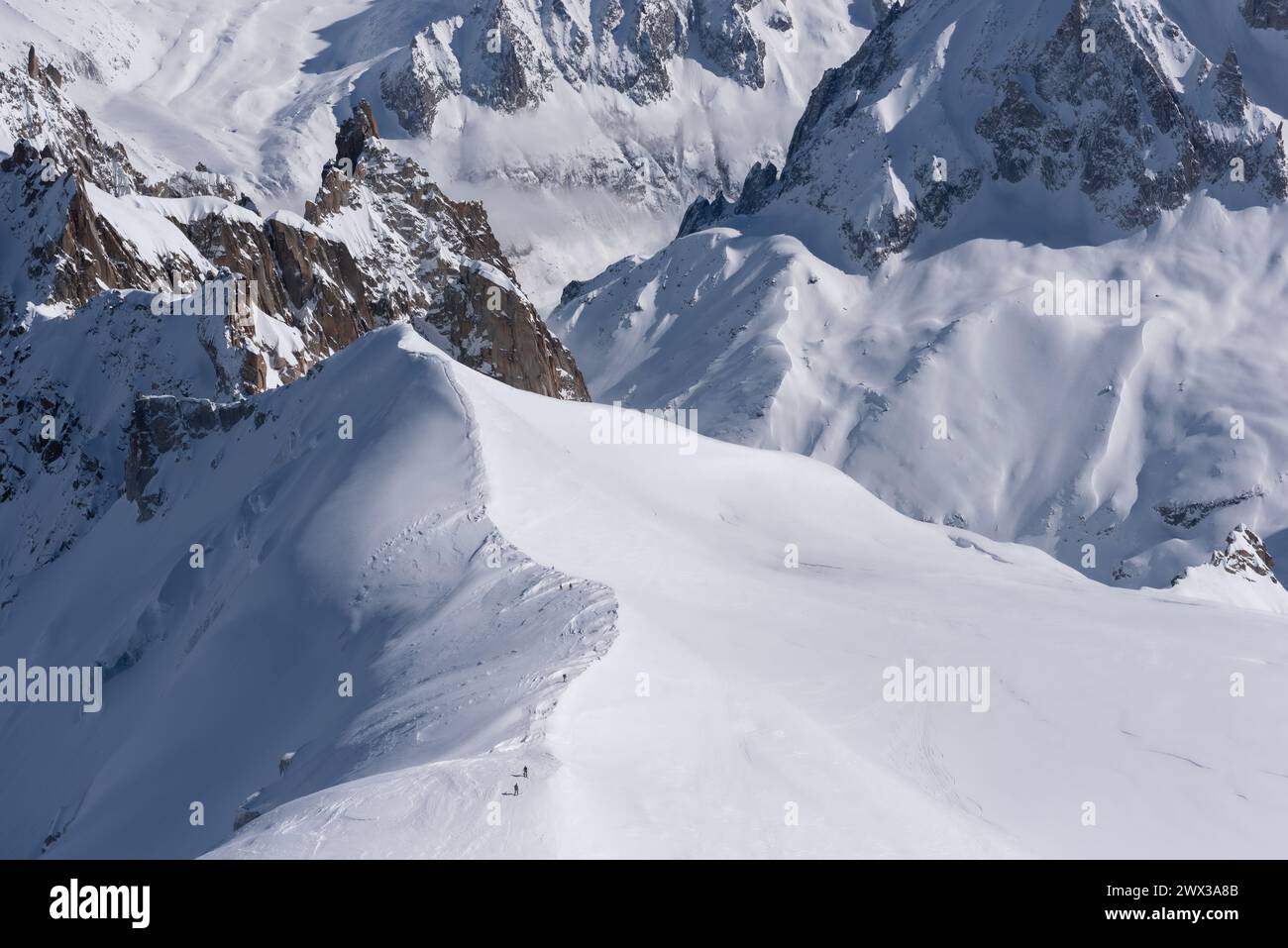 Groups of skiers skiing away on a snow covered ridge leading into the Vallee Blanche in the Mont ...