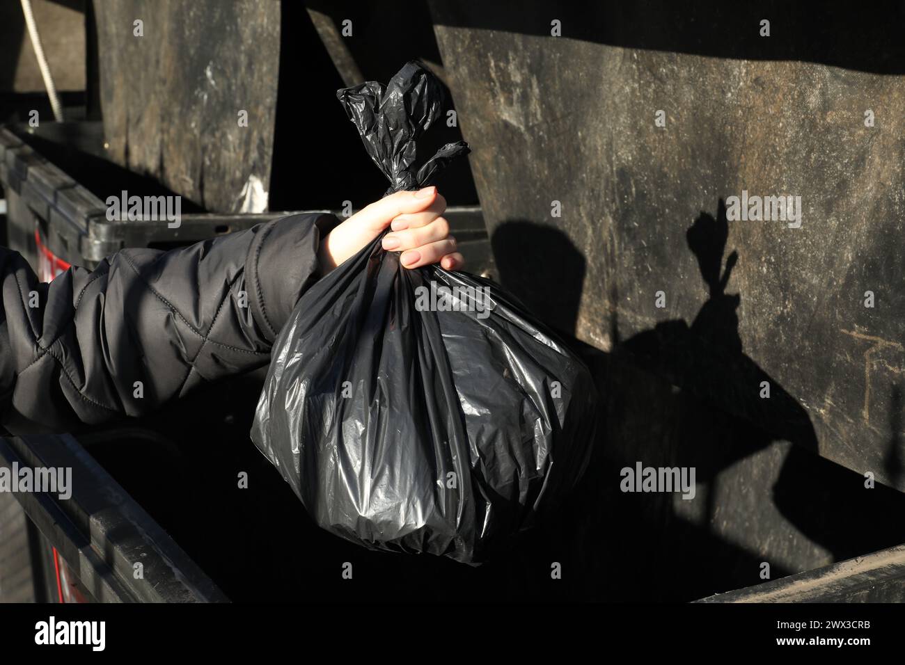 Woman throwing trash bag full of garbage in bin outdoors, closeup Stock ...