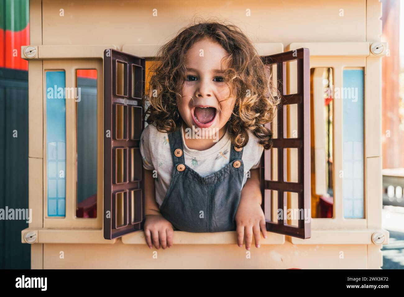 happy little boy looking out of a window in playground screaming with ...