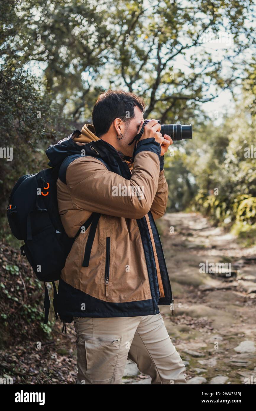 vertical portrait of young photographer on a route through a forest ...