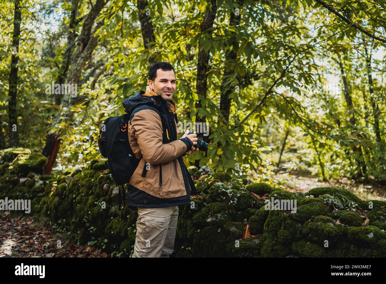 horizontal portrait of young photographer walking along a forest path ...