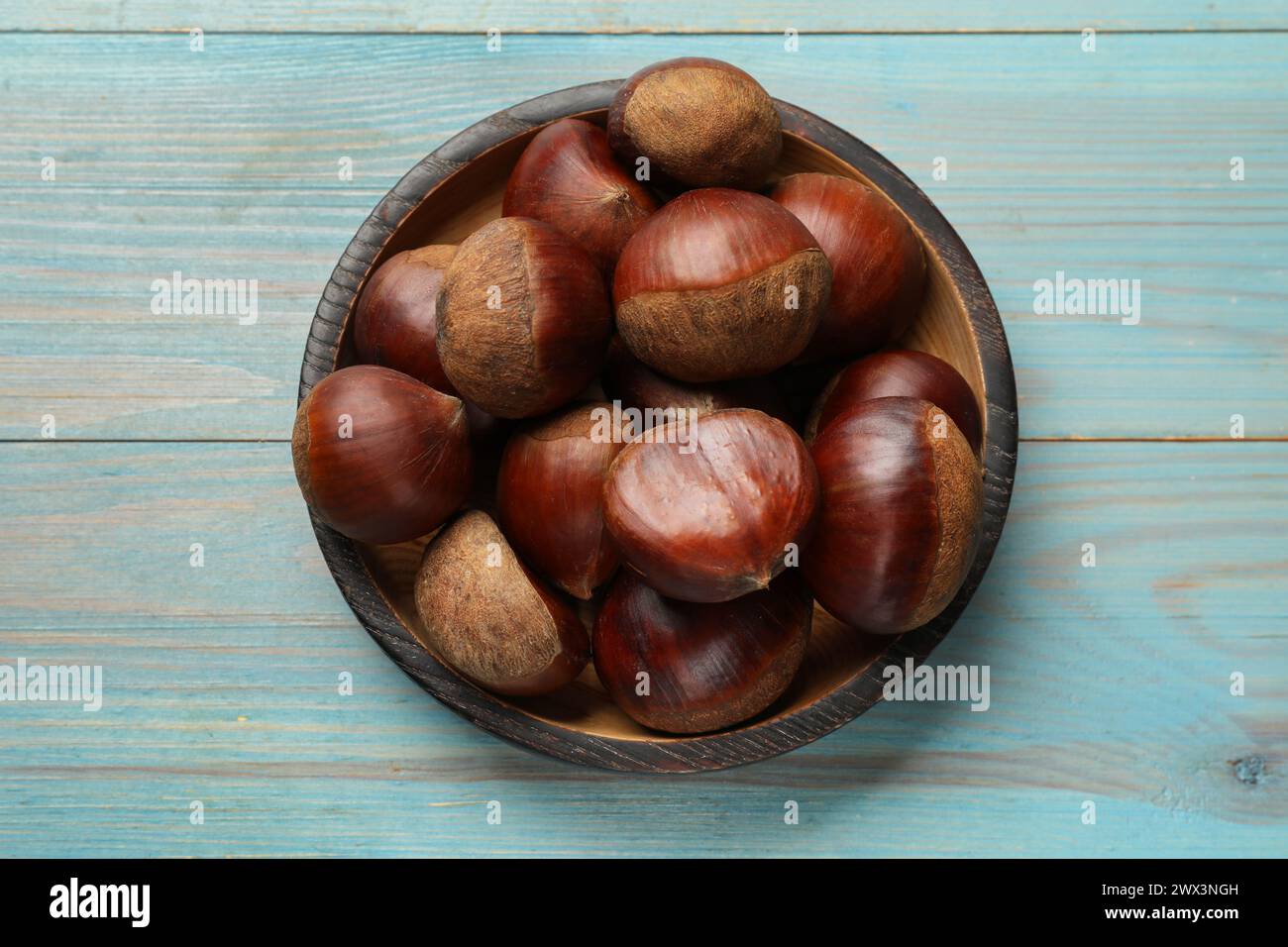 Roasted edible sweet chestnuts on light blue wooden table, top view ...