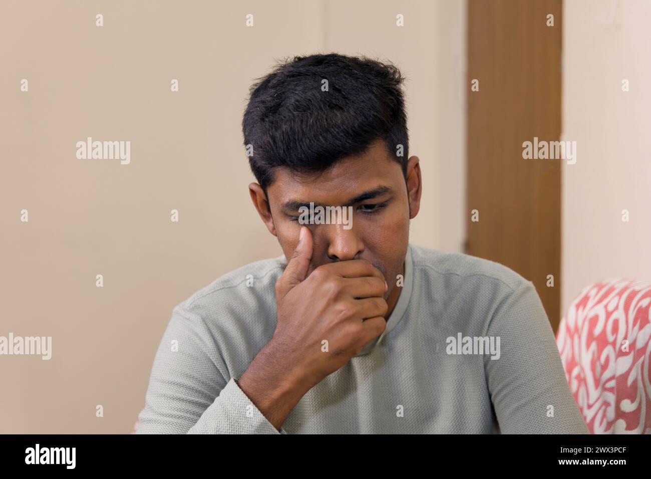 An image of a South Asian man looking downcast and wiping tears from ...