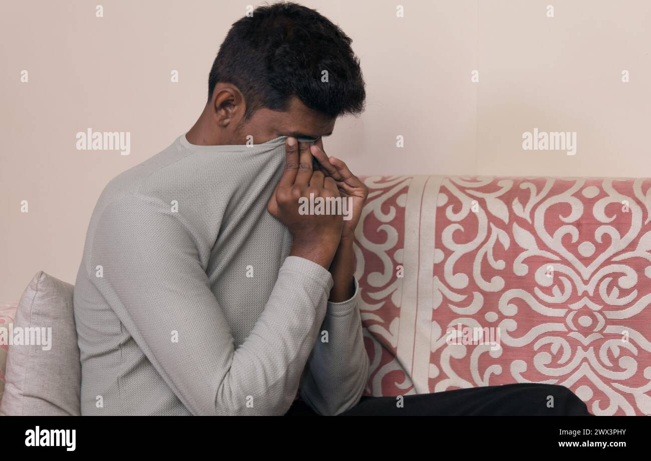 A photo of a young man looking dejected and slumped on a couch at home ...