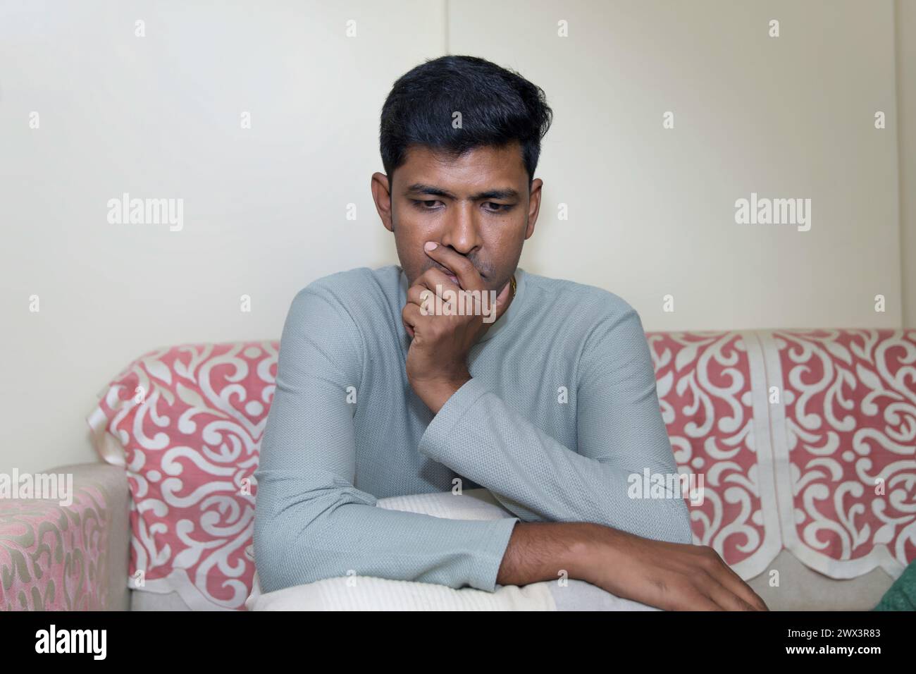 Indian man sadly sitting on the sofa at home Stock Photo - Alamy