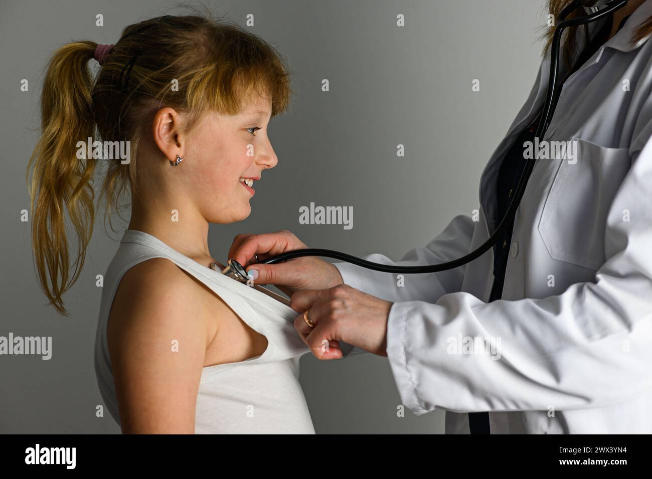 a doctor in a white coat with a stethoscope listens to the heartbeat of ...