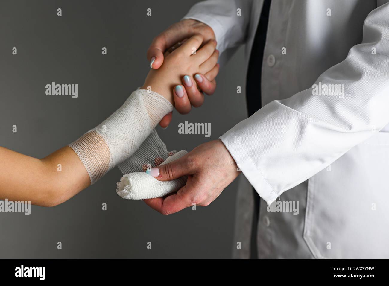 a doctor in a white coat with a stethoscope bandages the hand of a ...