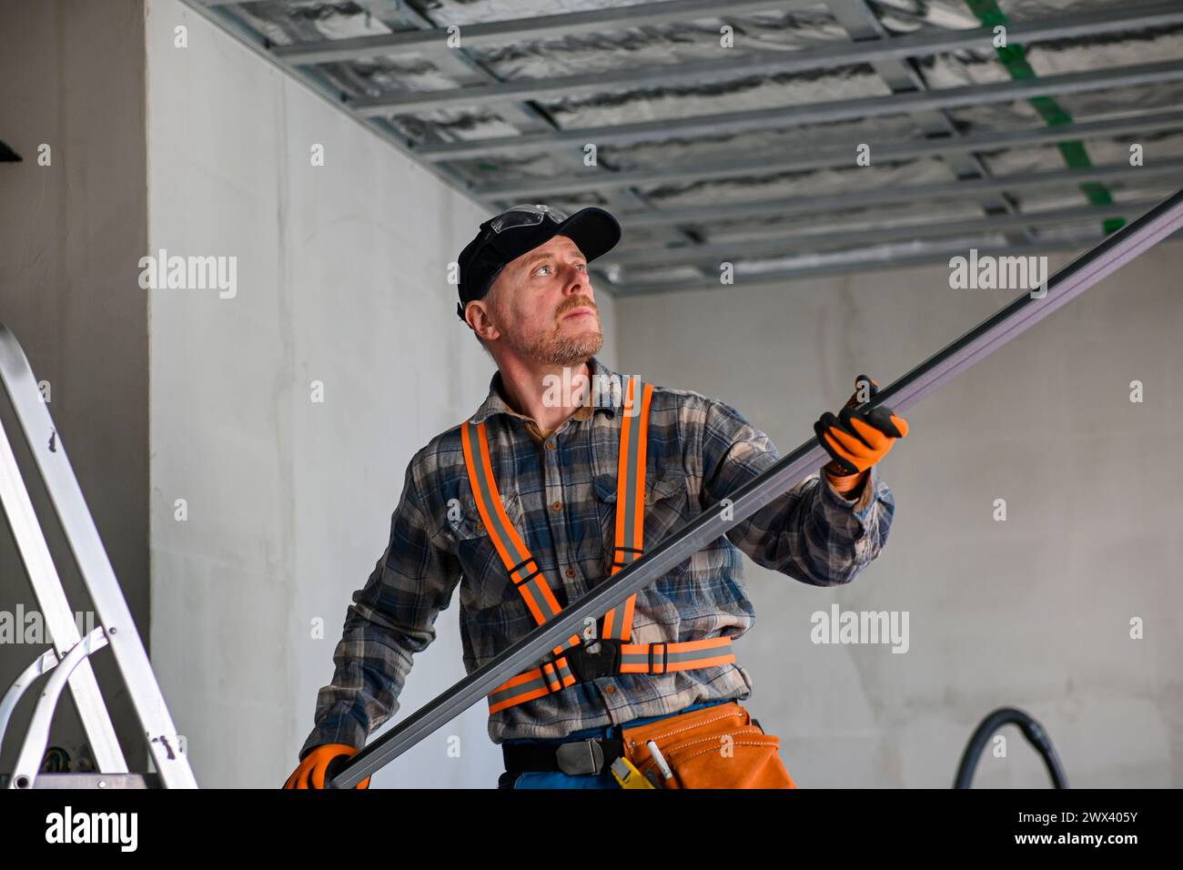 construction worker in overalls, gloves and tool belt assembles iron ...
