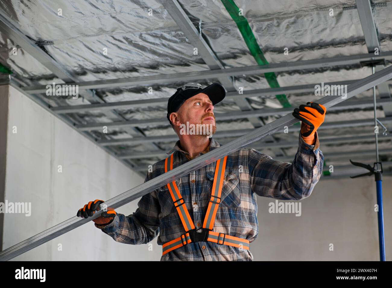 construction worker in overalls, gloves and tool belt assembles iron ...