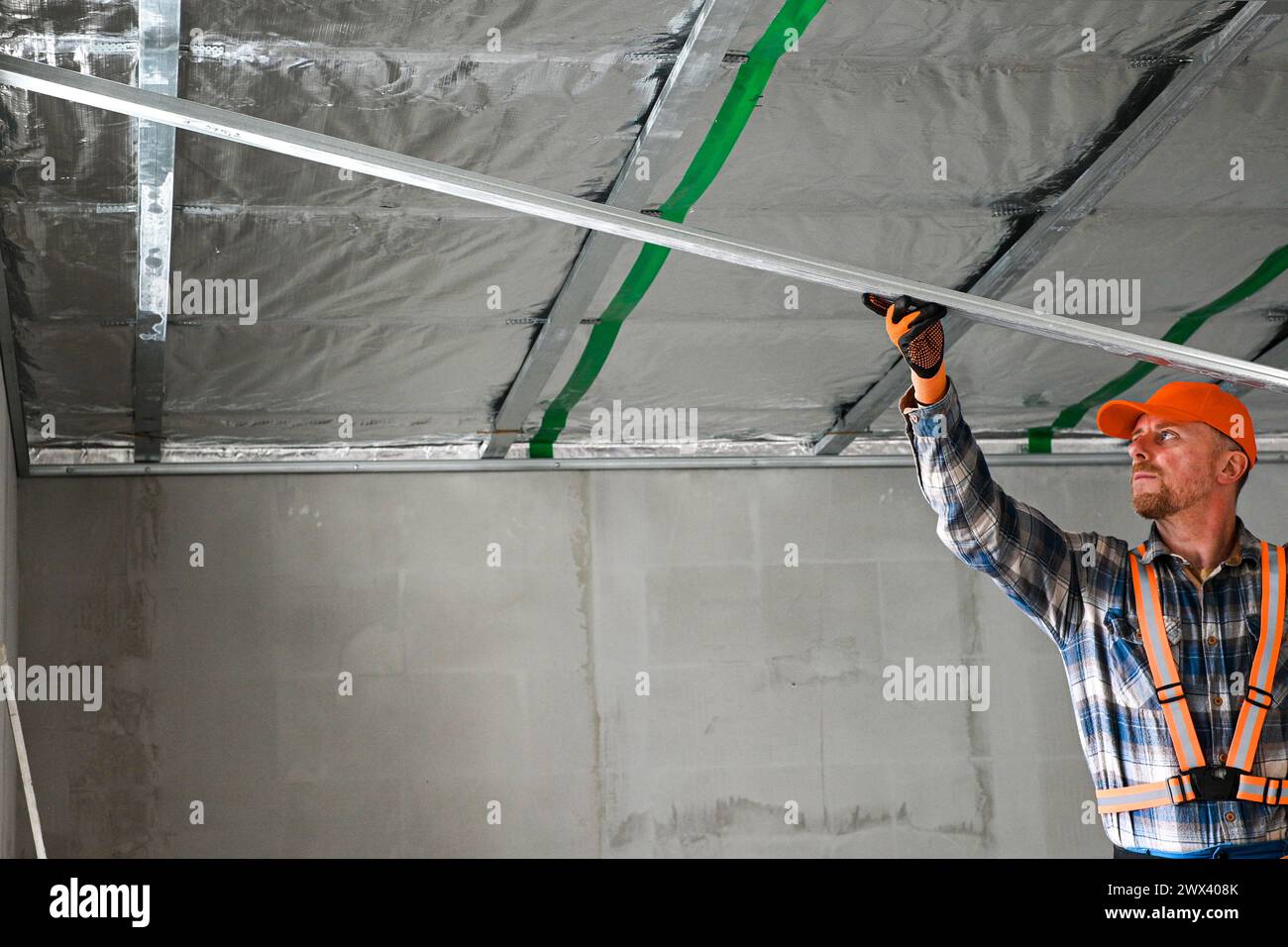 construction worker in overalls, gloves and tool belt assembles iron ...
