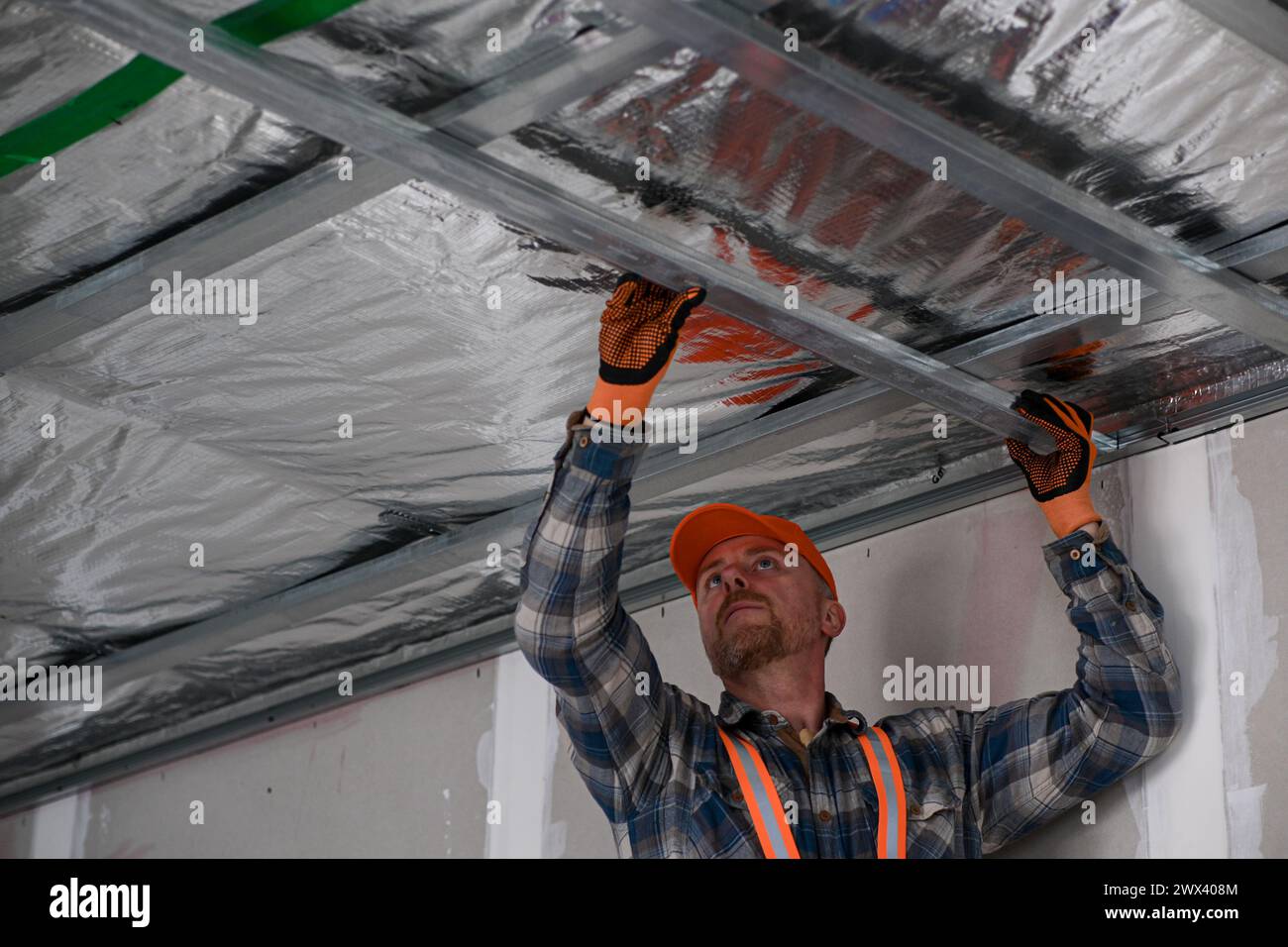 construction worker in overalls, gloves and tool belt assembles iron ...